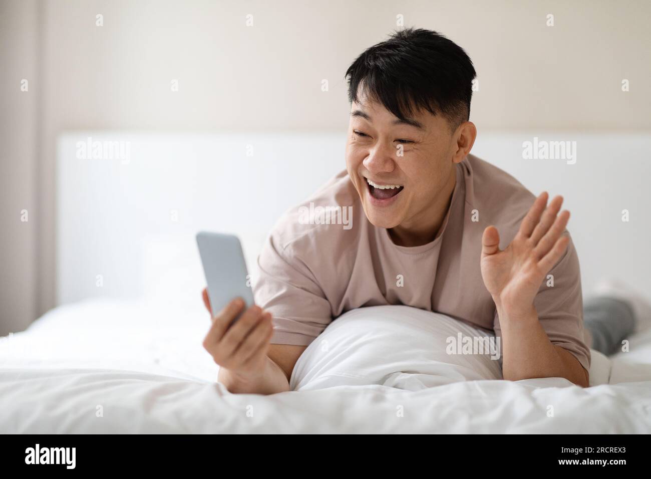 Thrilled relaxed asian man have video call with friends Stock Photo - Alamy