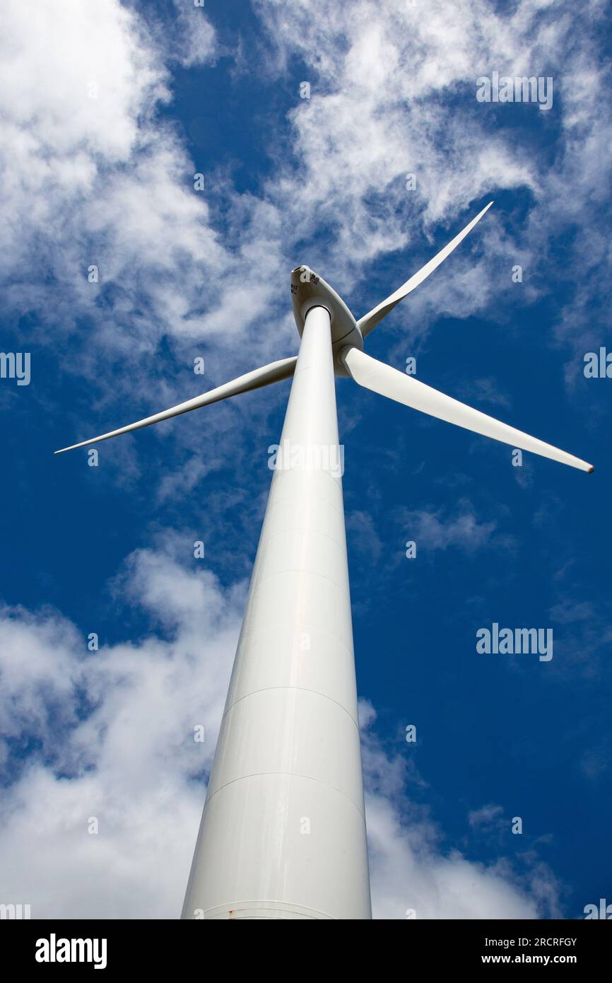 Upward view from tower base to white blades of wind turbine generator ...