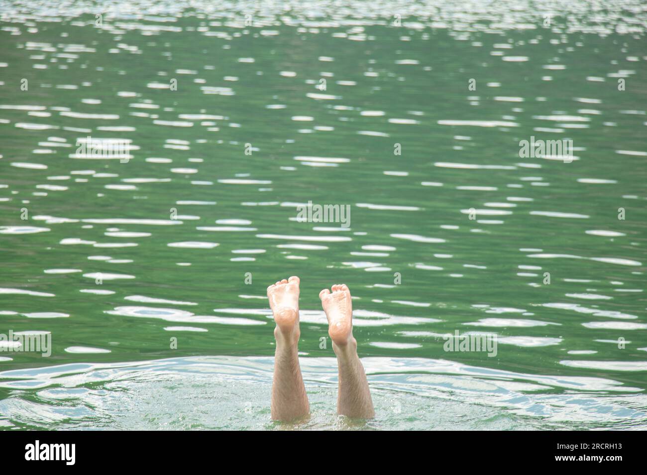 Men's legs stick out of the water in a quarry in Ukraine during ...