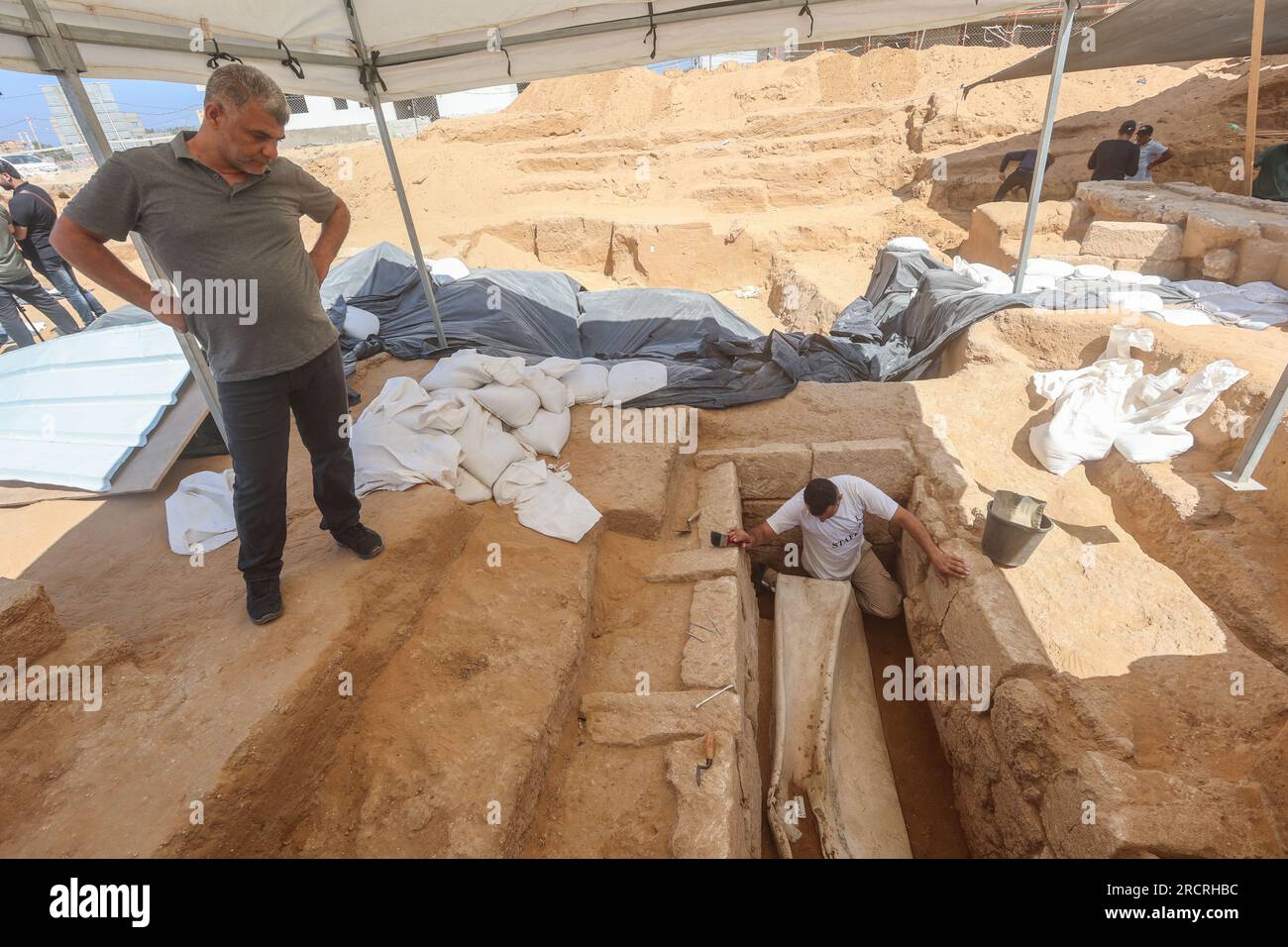 A Palestinian Archaeologist Removes The Sand From A Lead Sarcophagus