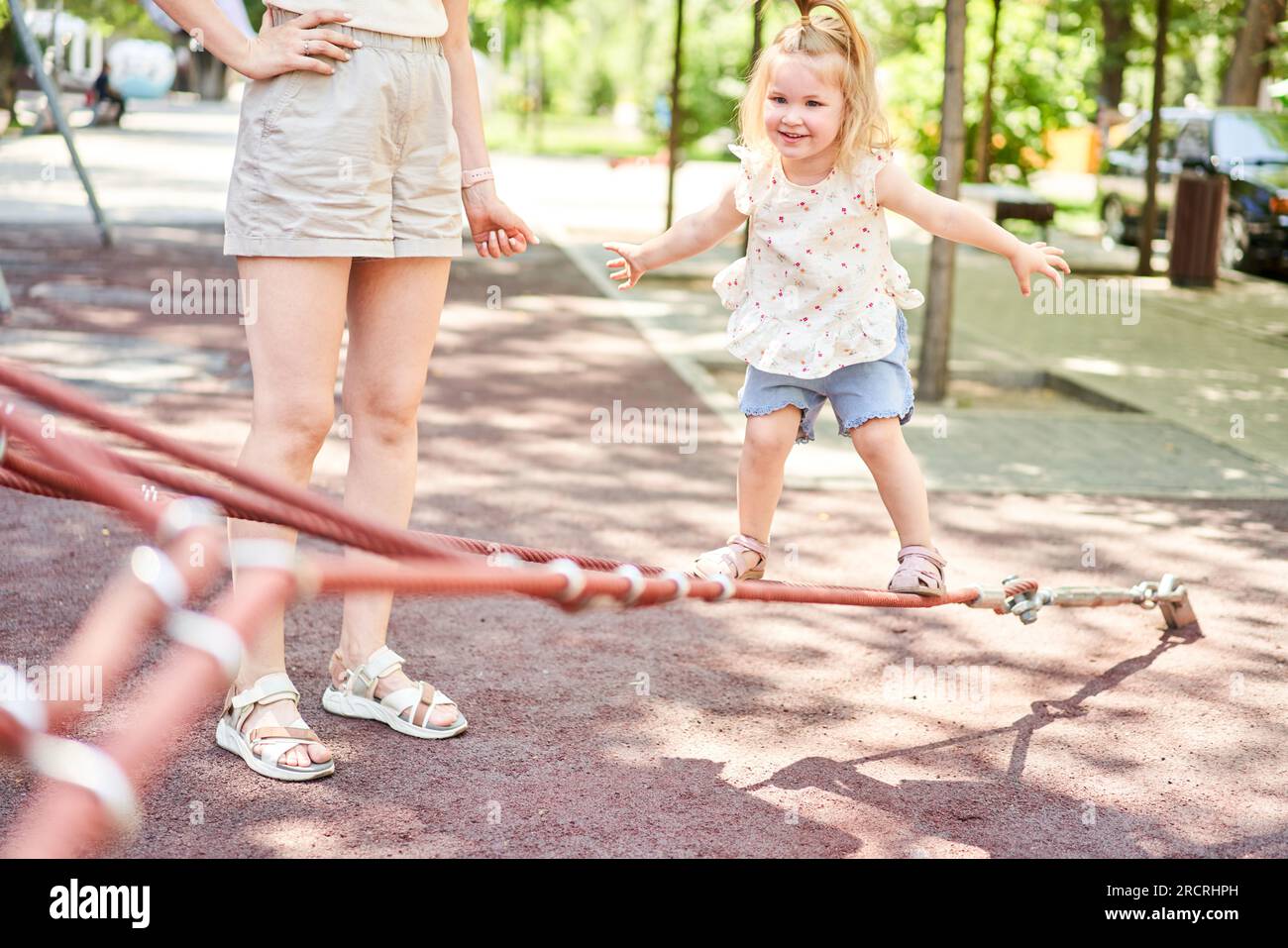 Active little child playing on climbing net and jumping on trampoline ...
