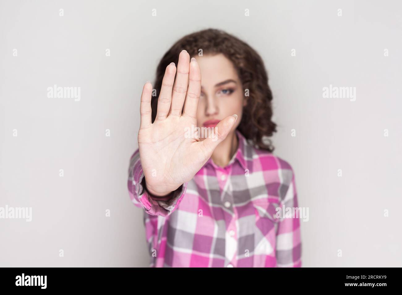 Woman with curly hair showing stop sign, prohibition symbol, keeps palm ...