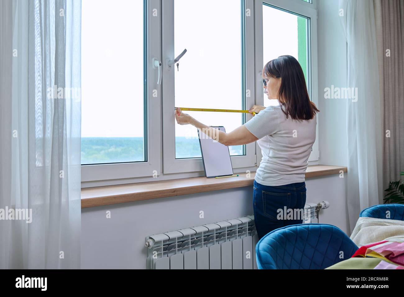 Woman measuring window with tape measure, tailoring service Stock Photo ...