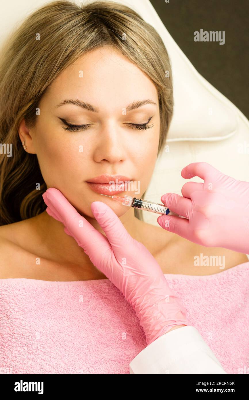 Cosmetician makes injections for lip augmentation beautiful woman. Lip ...