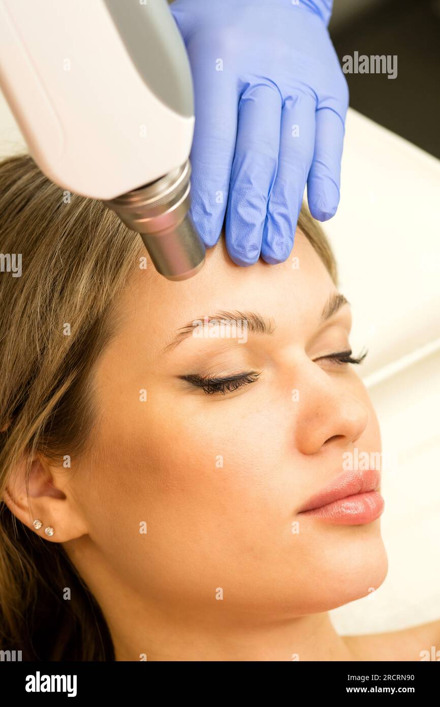 Woman undergoing laser removal permanent makeup. Esthetician removes ...