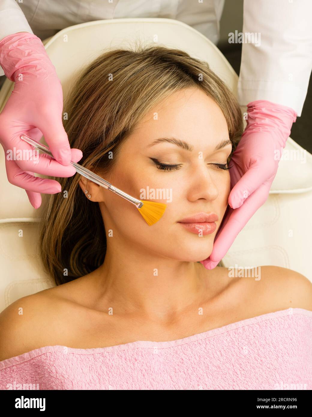 Young woman during face peeling procedure in beauty salon. Acid organic ...