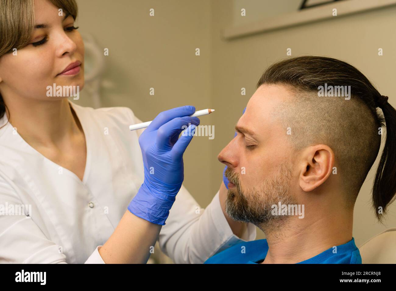 Cosmetician marking dermographic pencil face male patient to perform an ...