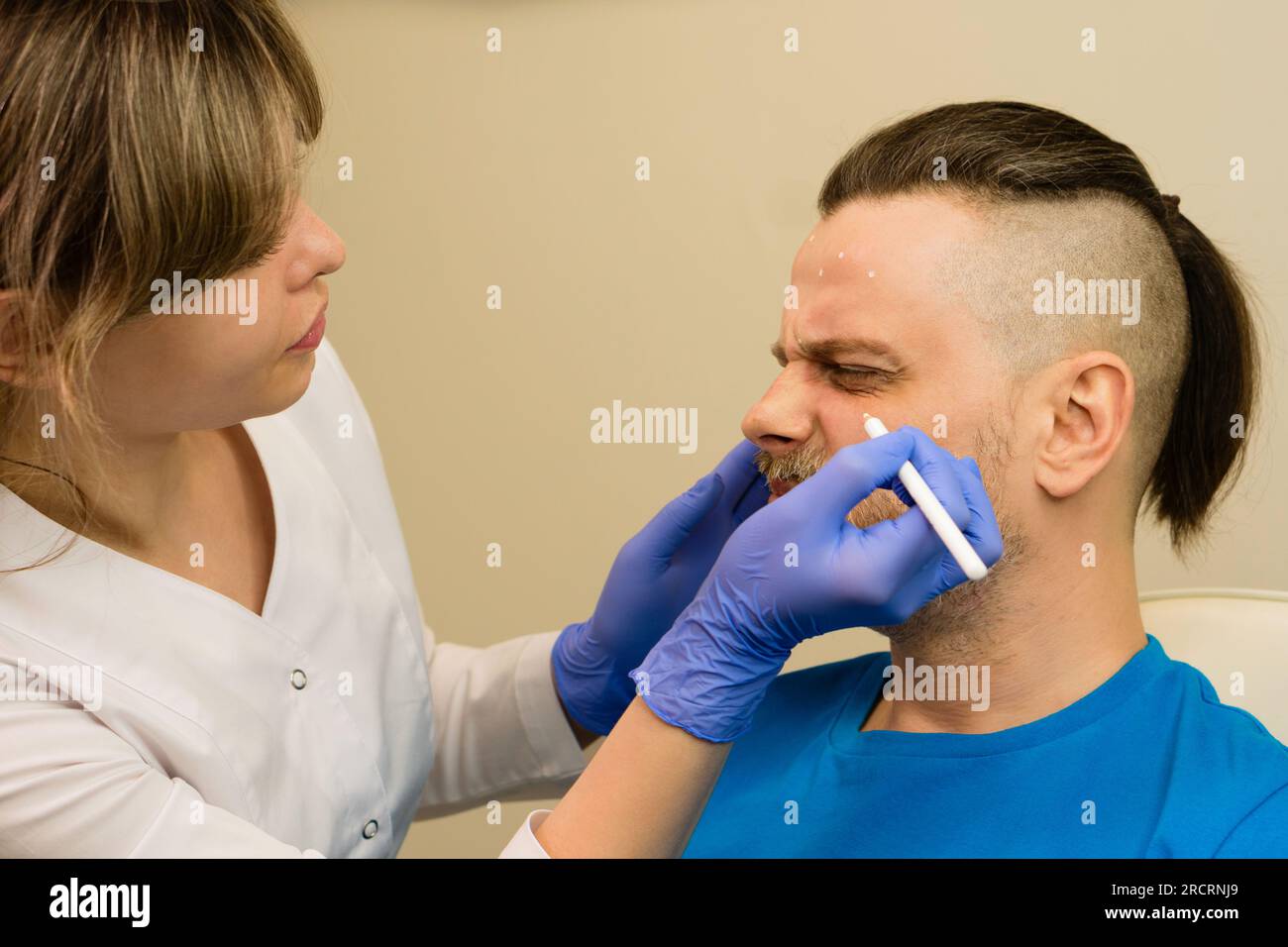Cosmetician marking dermographic pencil face male patient to perform an ...