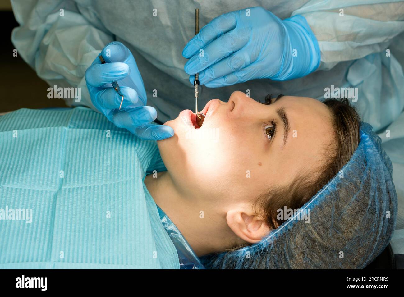 Dental Surgeon Examines Female Patients Mouth Before Removing Wisdom