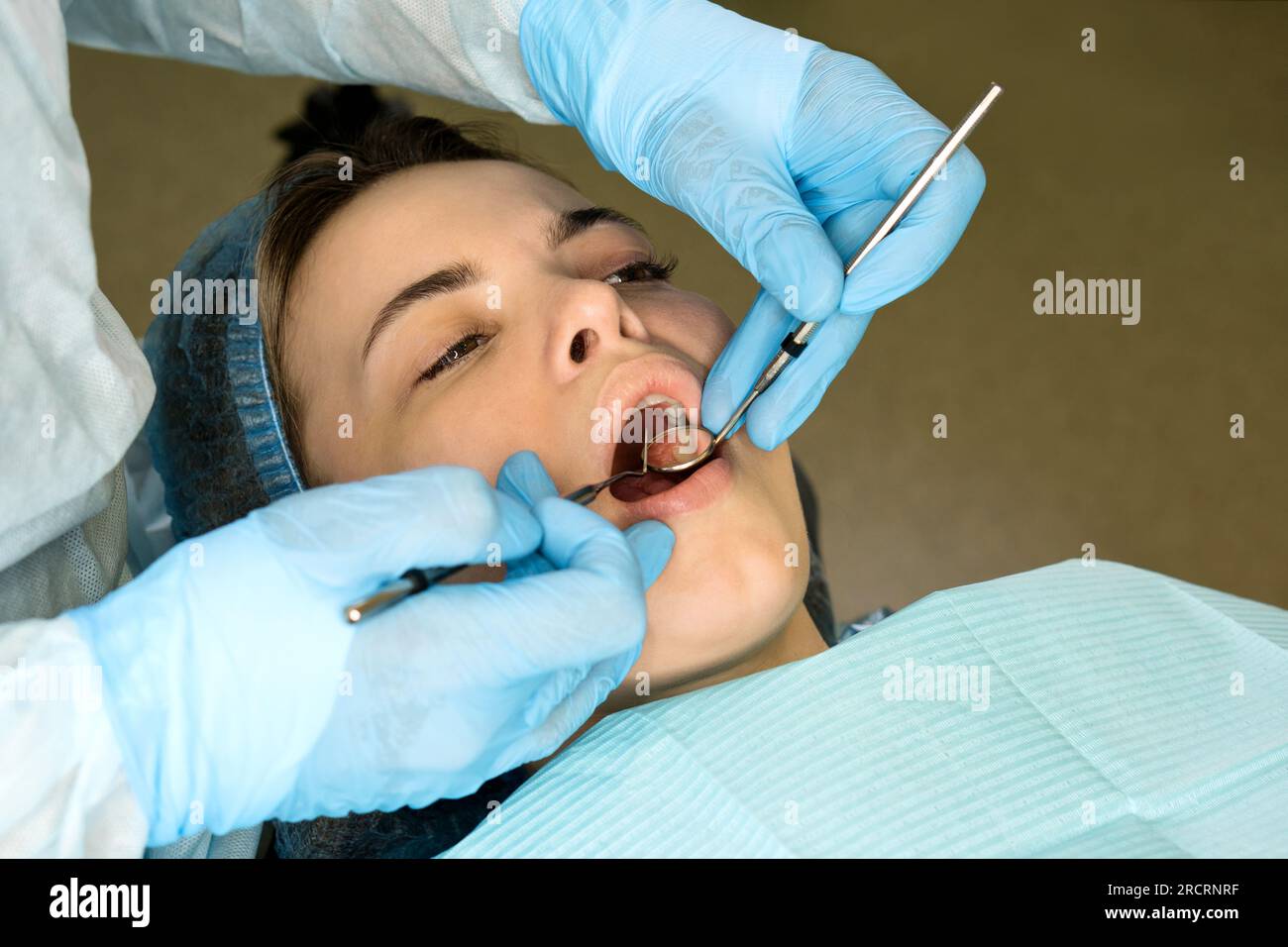 Dental surgeon examines female patient's mouth before removing wisdom ...