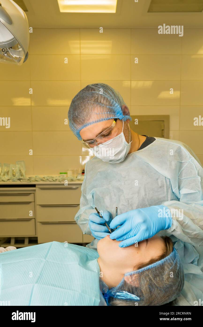 Dental surgeon examines patient's mouth before removing wisdom tooth, the maxillary third molar ...