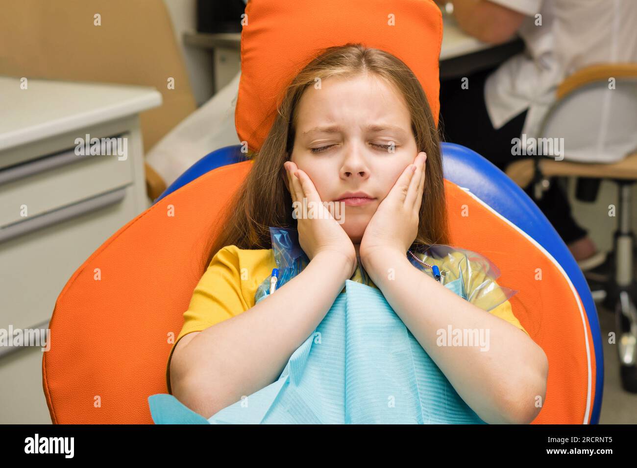 Schoolgirl experiencing severe toothache while sitting in dental chair ...