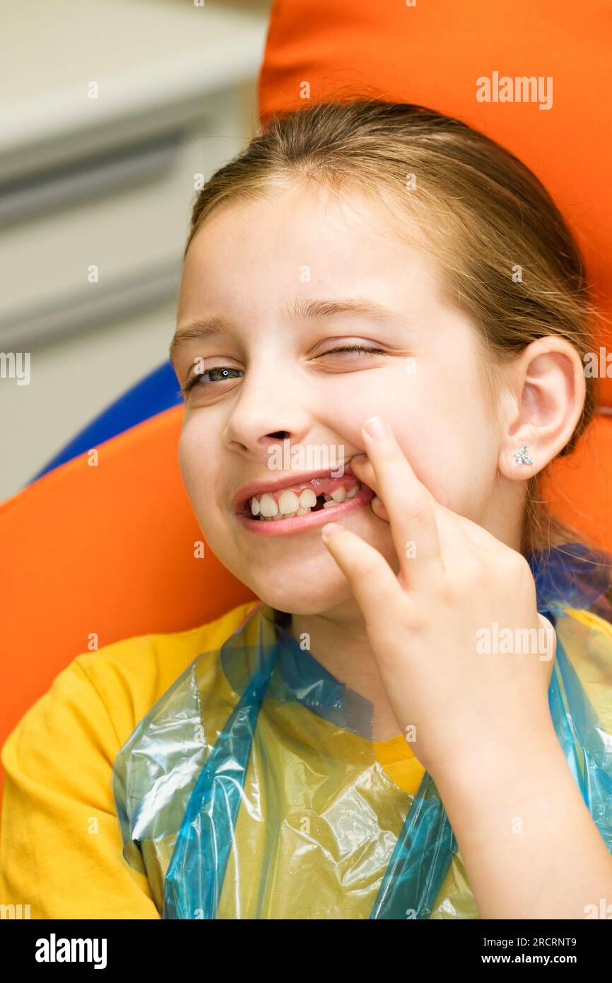 Schoolgirl showing mouth with second teeth and lost milk teeth while ...