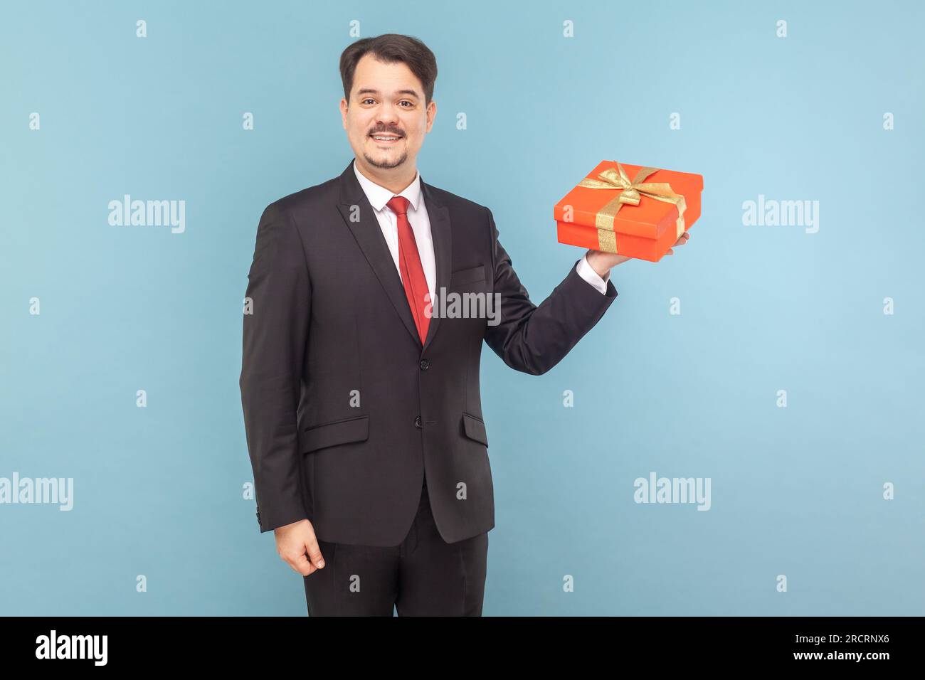 Portrait of satisfied cheerful man with mustache standing holding red ...