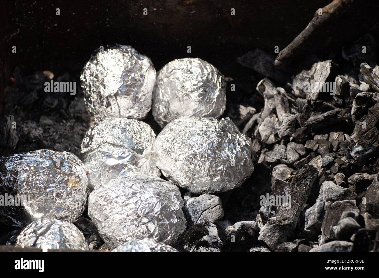 Bake potatoes in foil on the grill in the coals in the summer at a ...