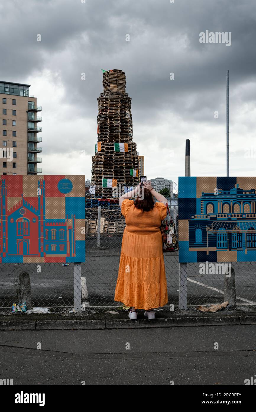 A woman dressed in orange takes a picture with her phone of the ...