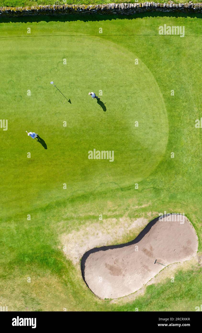 Golf course green aerial view and two players Stock Photo - Alamy