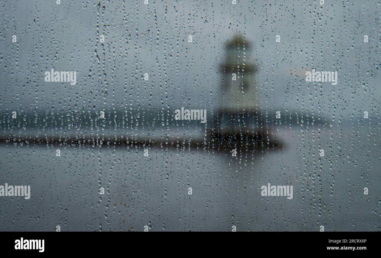 rainy view through cruise window of lighthouse on the waterfront of ...