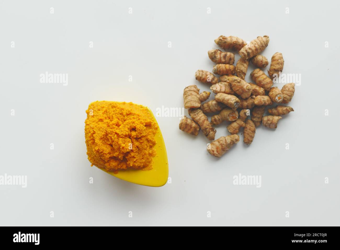 turmeric root and paste in a bowl on white background Stock Photo - Alamy