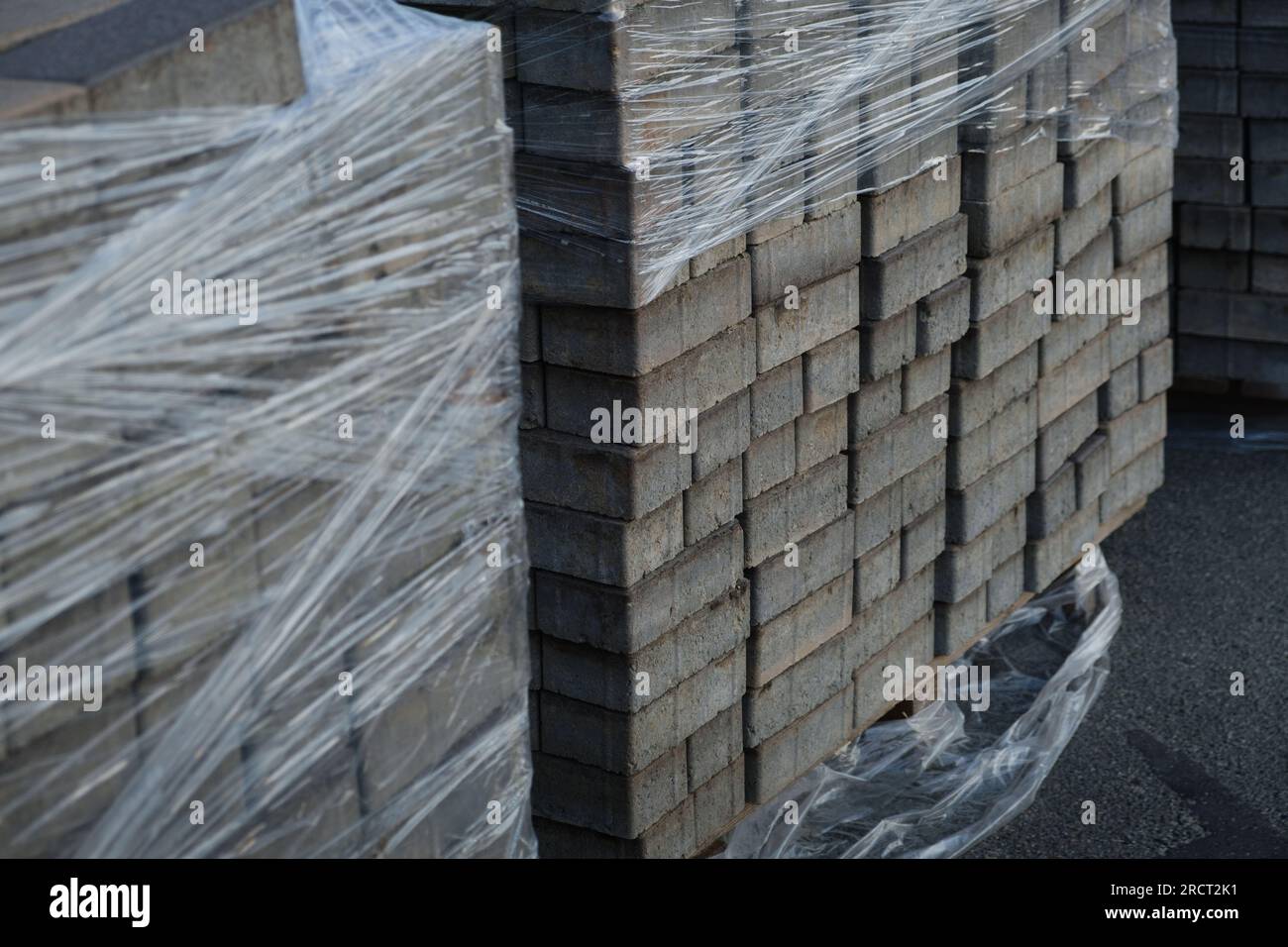 Packs of gray cement paving slabs are wrapped in plastic wrap in the ...