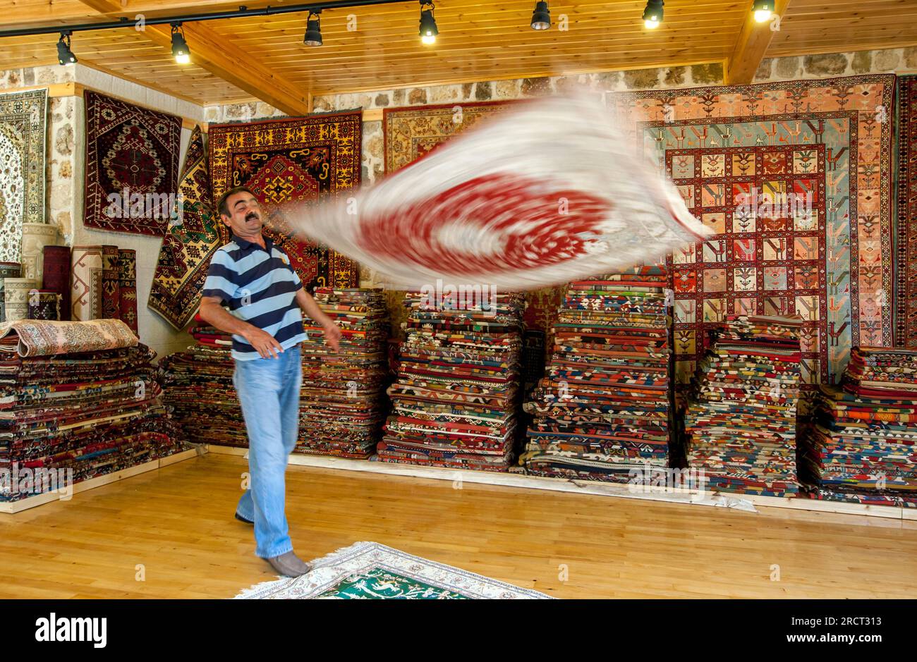 A Turkish carpet seller demonstrates the art of carpet spinning inside ...