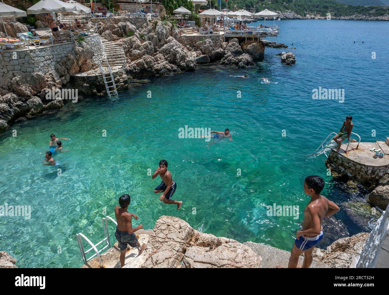 Turkish boys enjoy swimming in the Mediterranean Sea off the rock beach ...