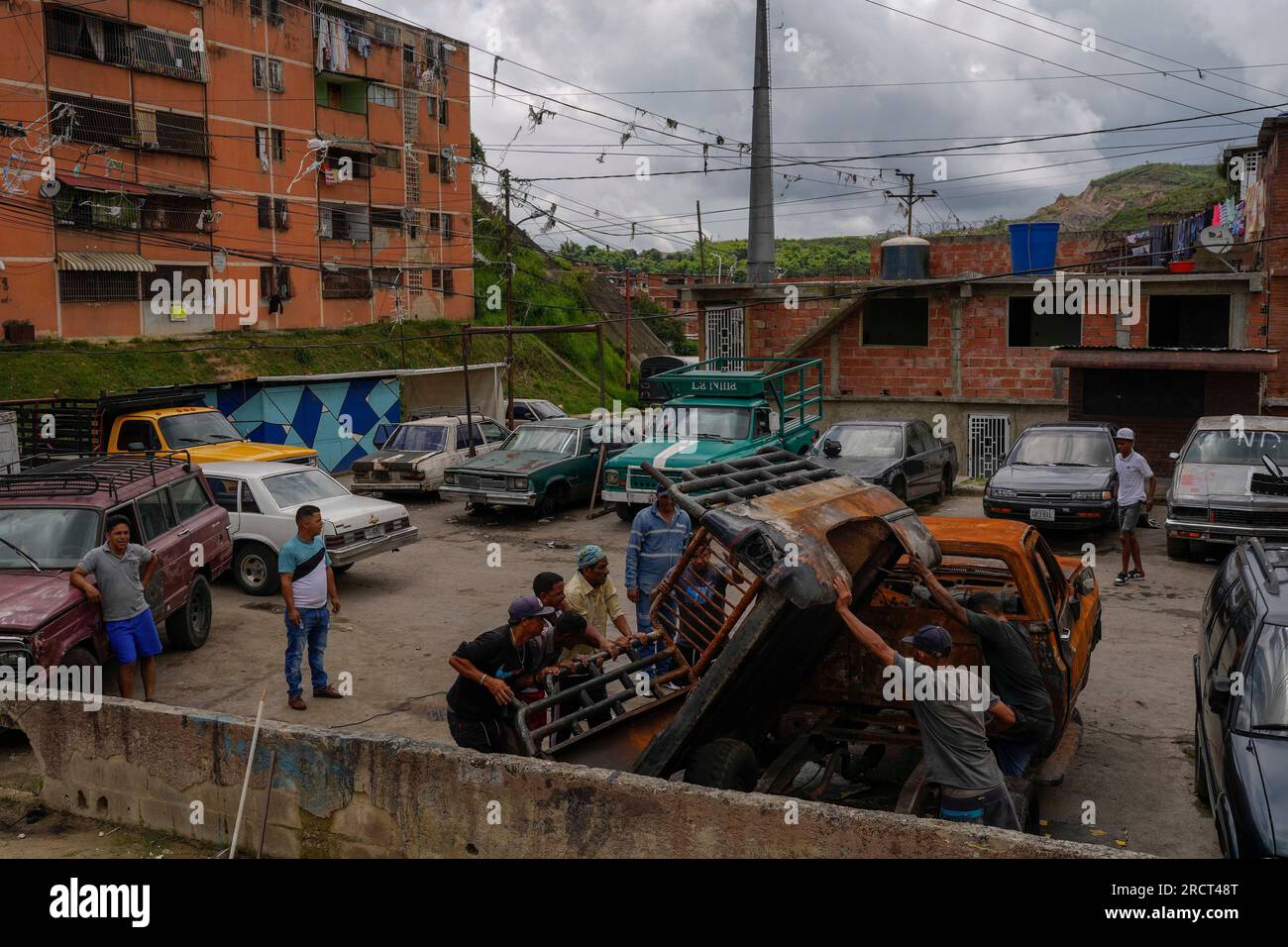 Men detach the back of a burned van in the Petare neighborhood of ...