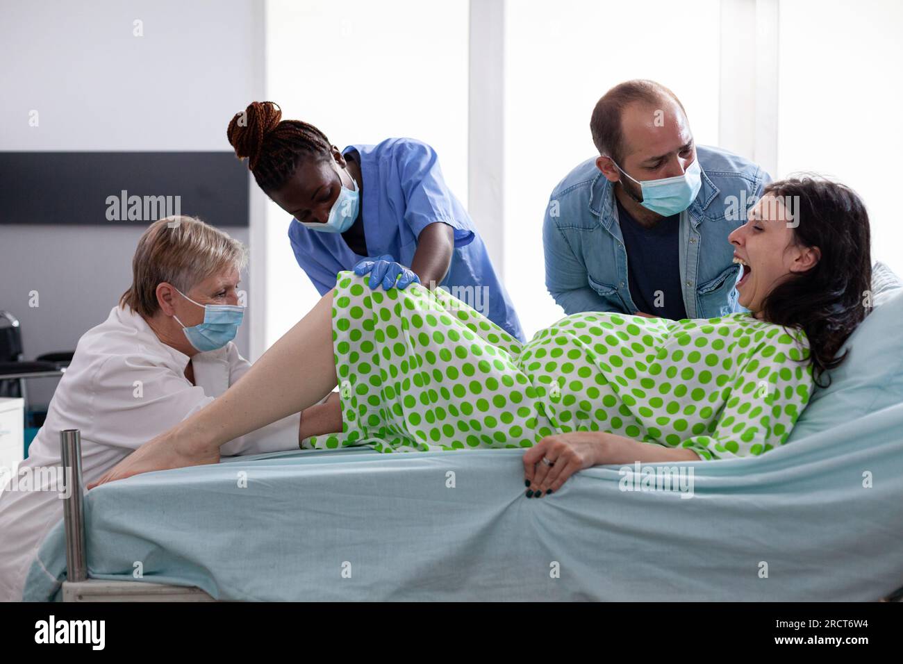 Future mother pushing during child birth, standing with husband beside ...