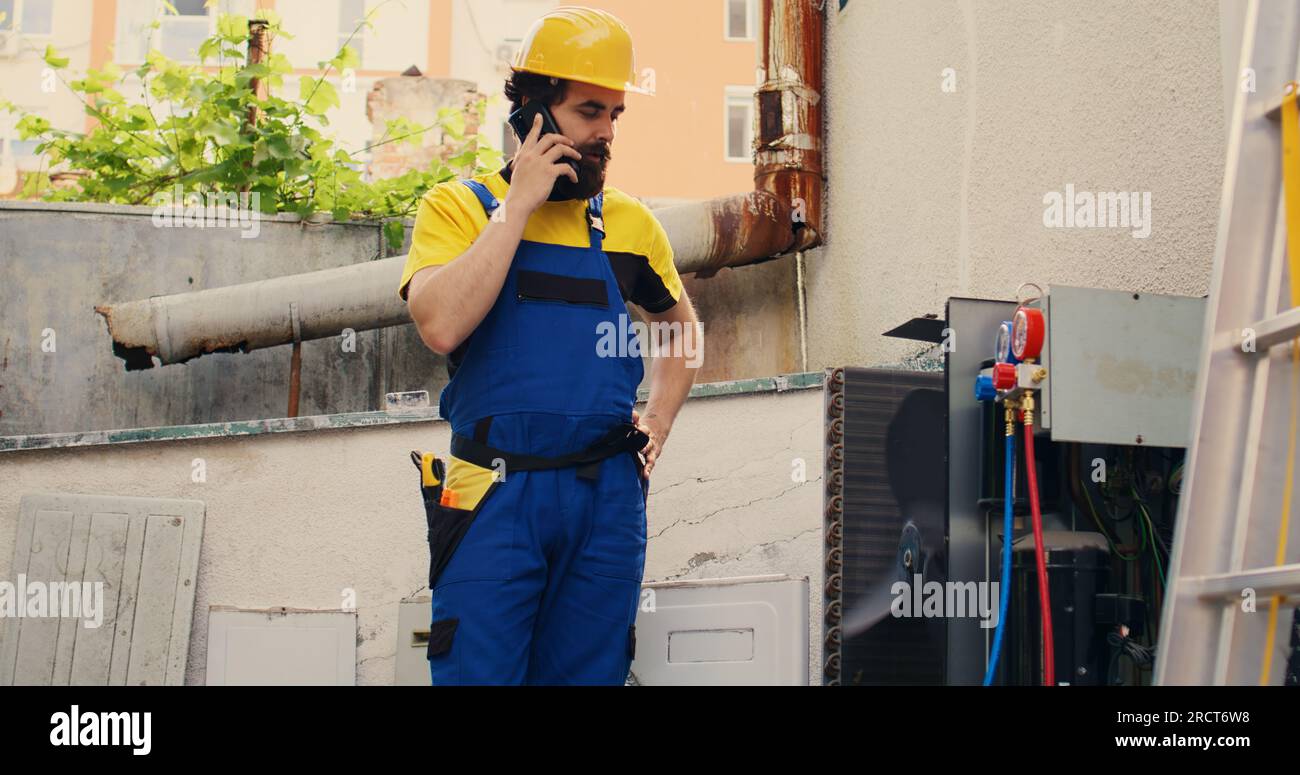 Skilled engineer on the phone with home owner after finishing hvac ...