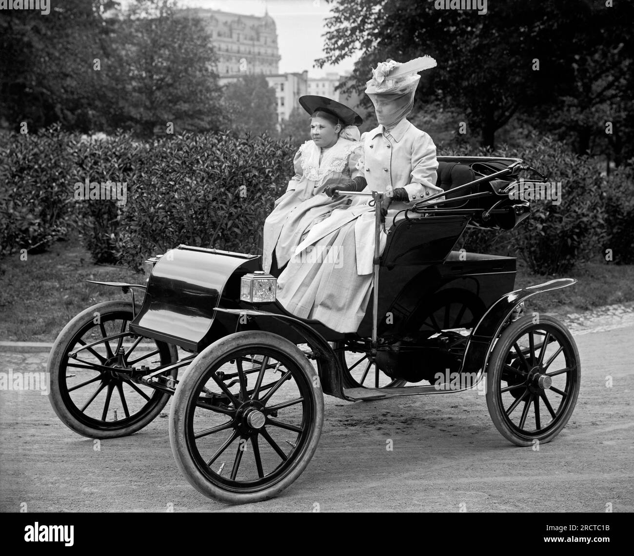 United States: c. 1906 Two women riding in a park in a very early ...