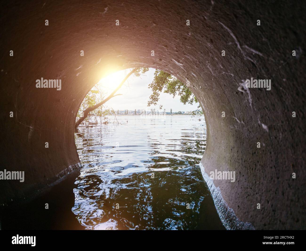 Light at end of round flooded sewer tunnel. Exit from sewer system ...
