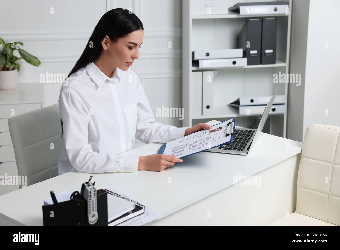 Human resources manager reading applicant's resume at white table in ...