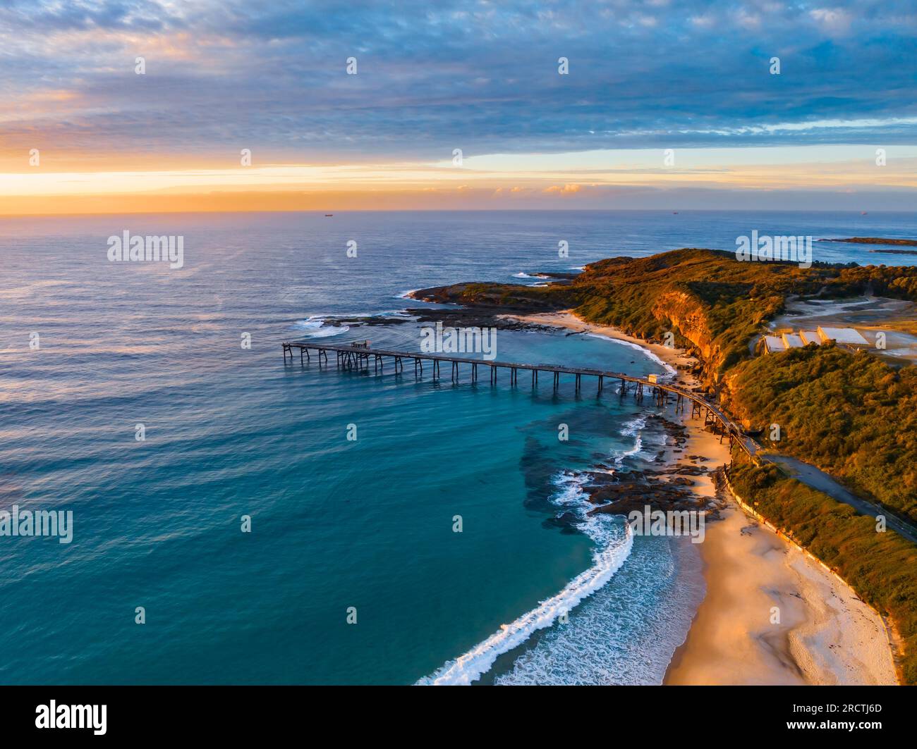 Sunrise seascape with cloud filled sky and the old coal loading jetty ...