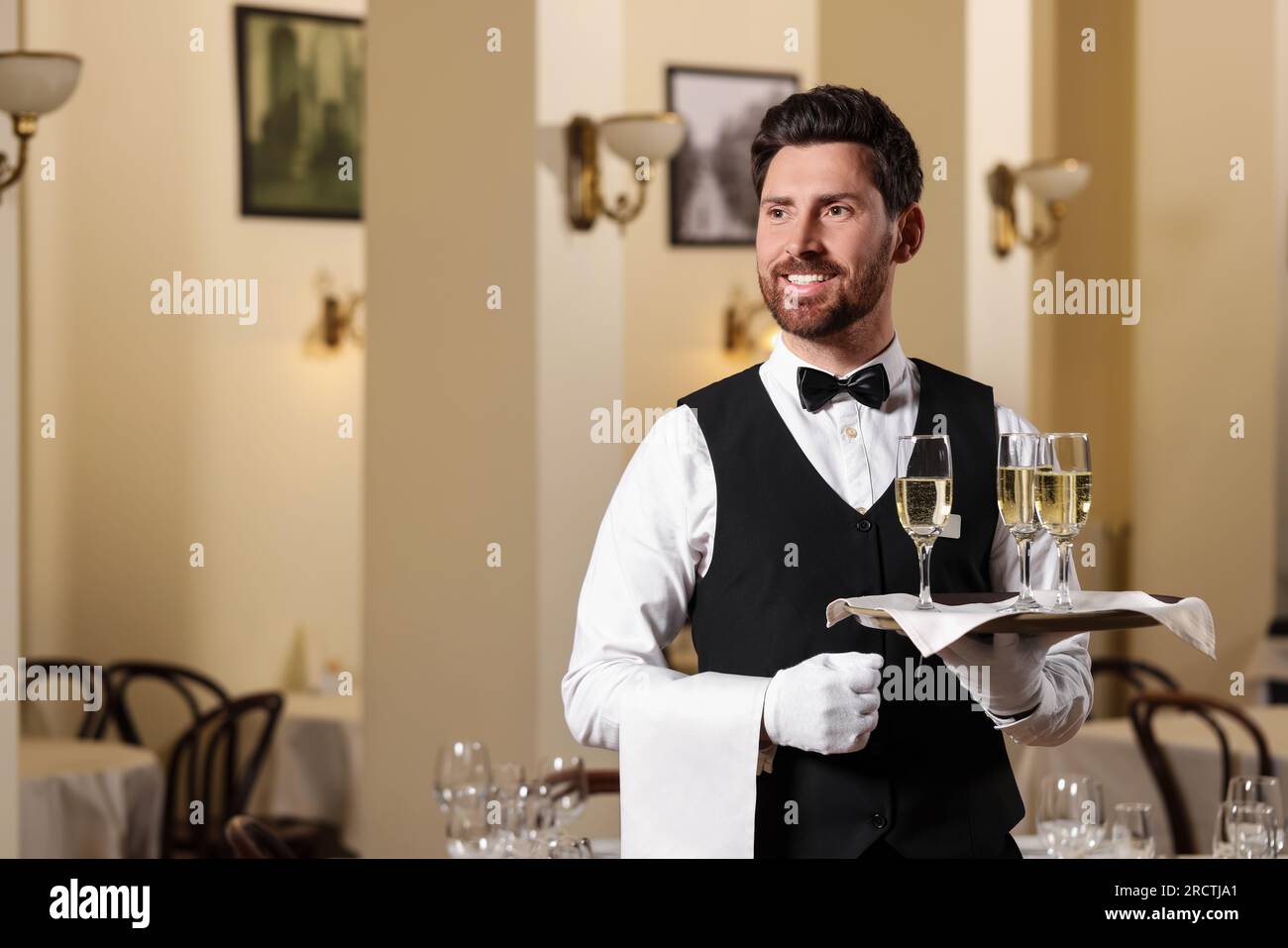Butler holding tray with glasses of sparkling wine in restaurant. Space ...