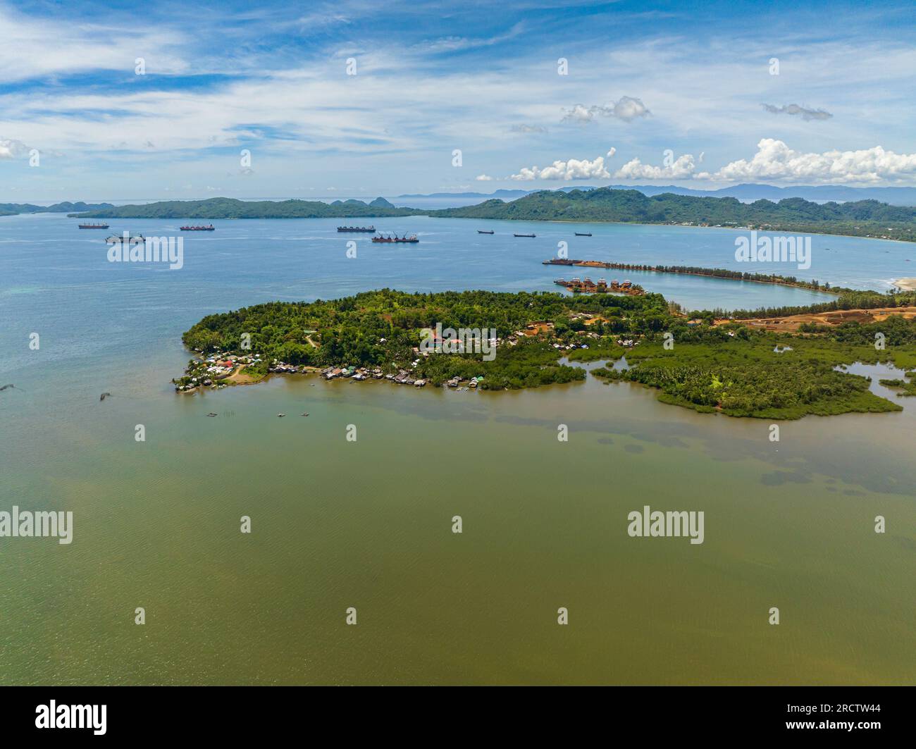 Tropical island and sea bay with cargo and merchant ship. Blue skies ...