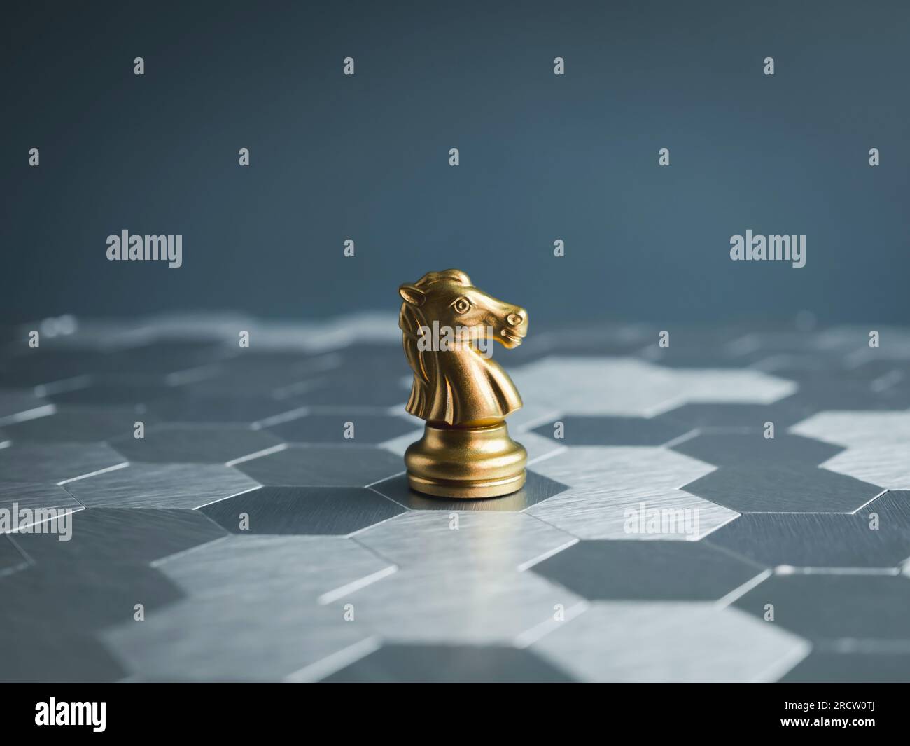 The golden horse, knight chess piece standing alone on silver hexagon ...