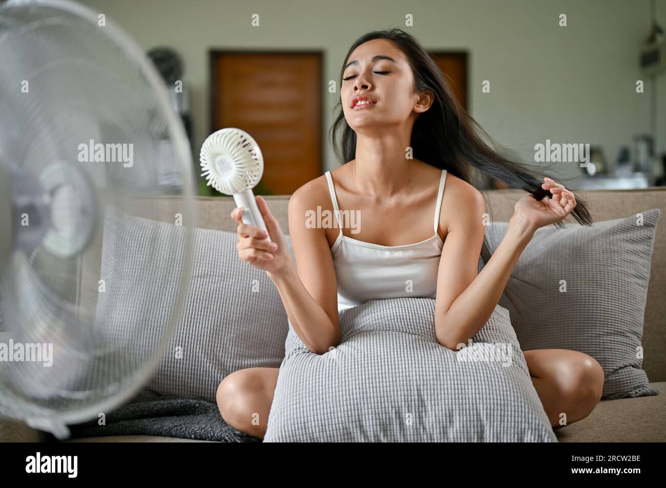 A tired and overheated Asian woman suffering from a heat attack, sits ...