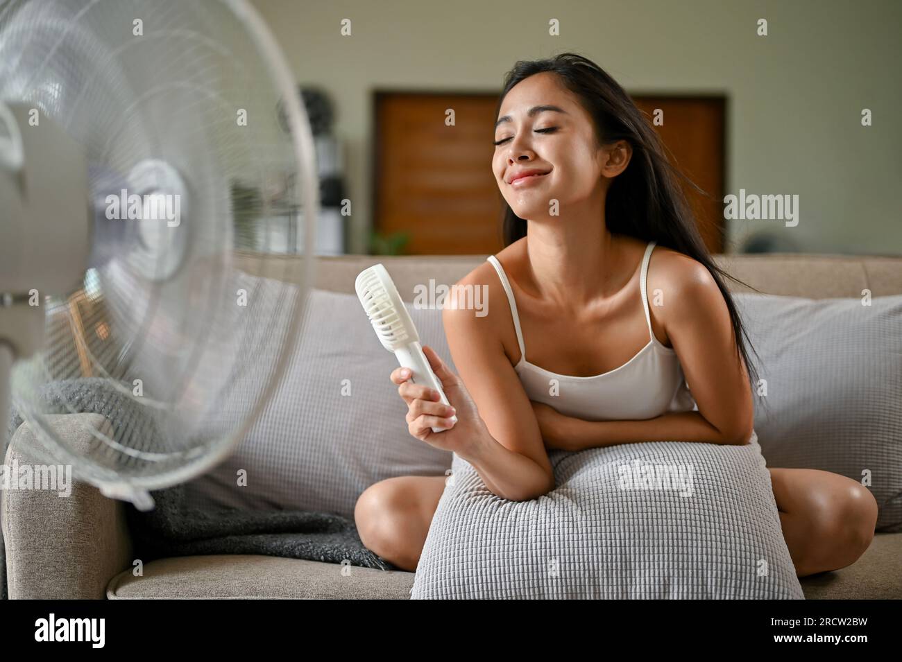 A gorgeous Asian woman, feeling hot suffering from a heat attack ...