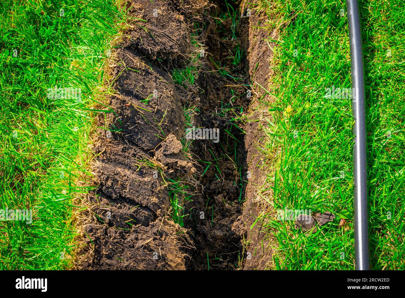A ditch dug in the lawn for laying pipes and installing irrigation ...