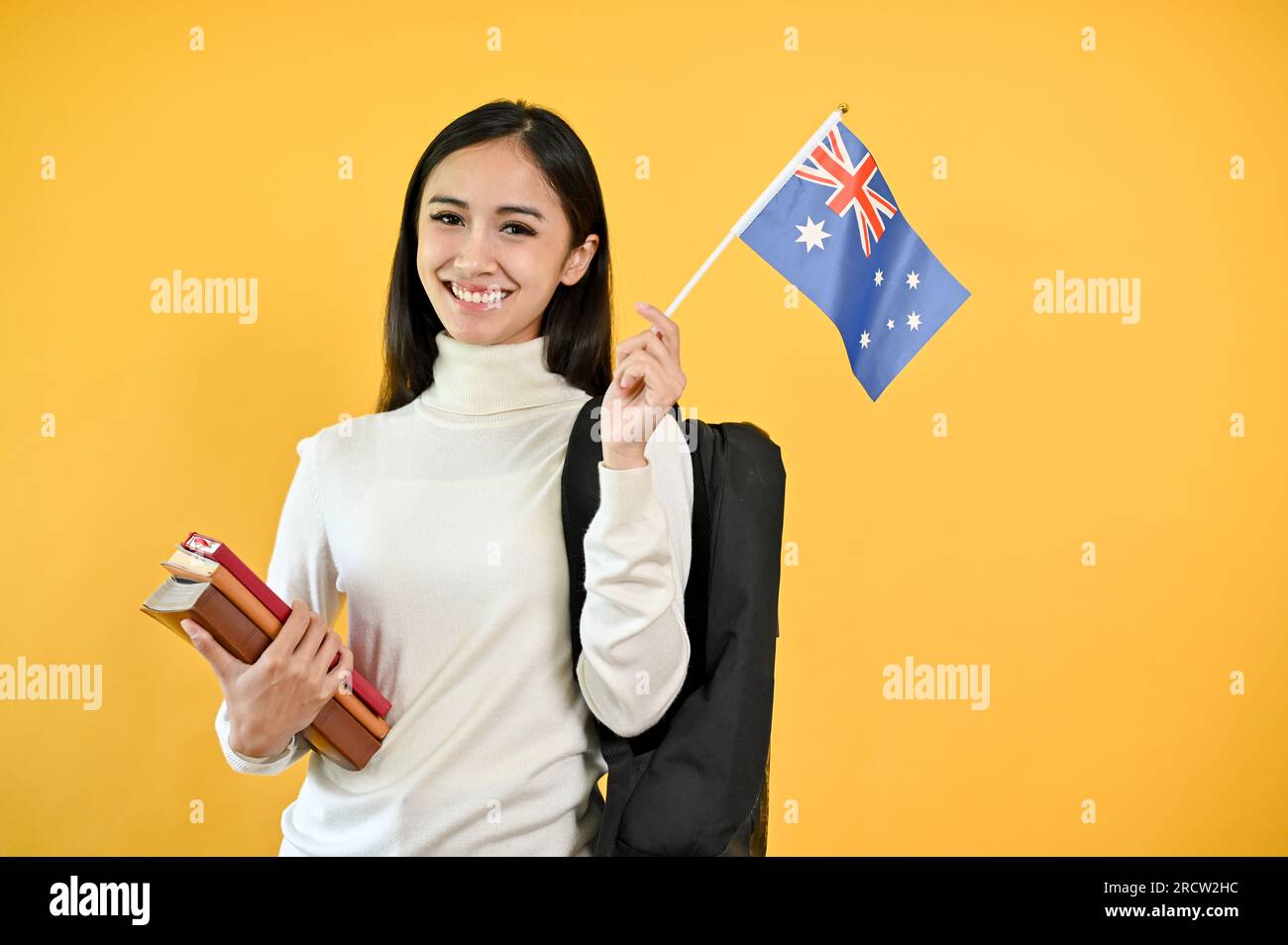 A pretty Asian female college student is holding her books and the ...
