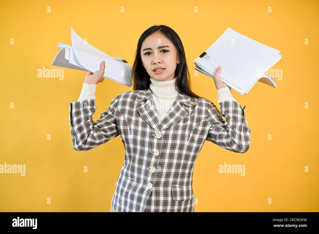 An unhappy and perplexed young Asian businesswoman stands against an ...