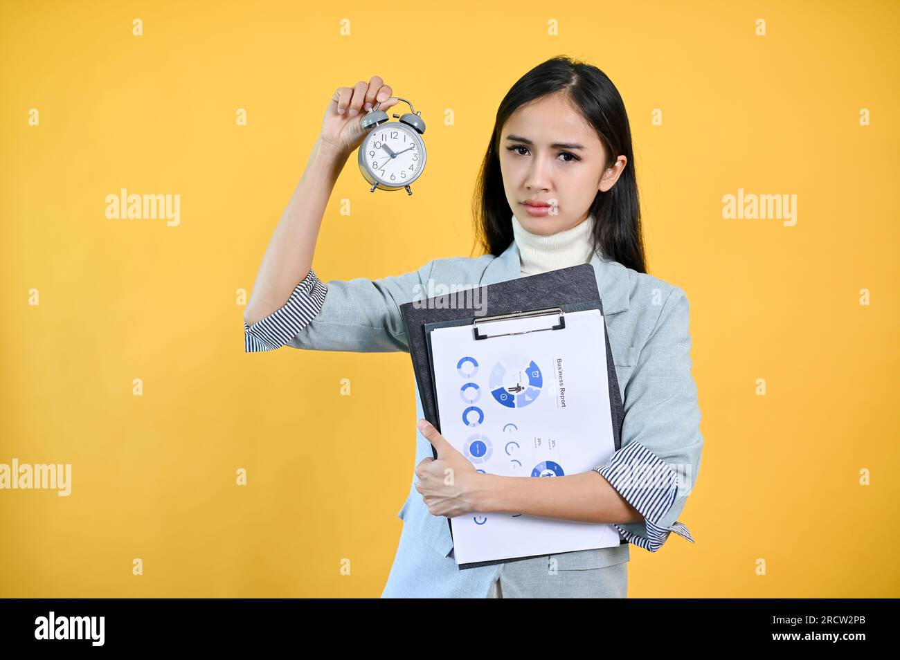 A beautiful Asian businesswoman holding documents and an alarm clock ...