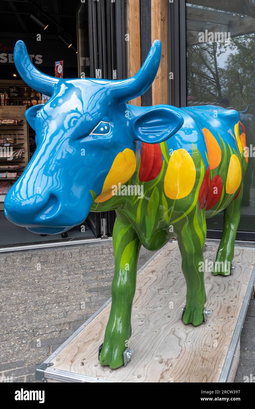 large blue cow with painted tulips outside a store at the Keukenhof ...