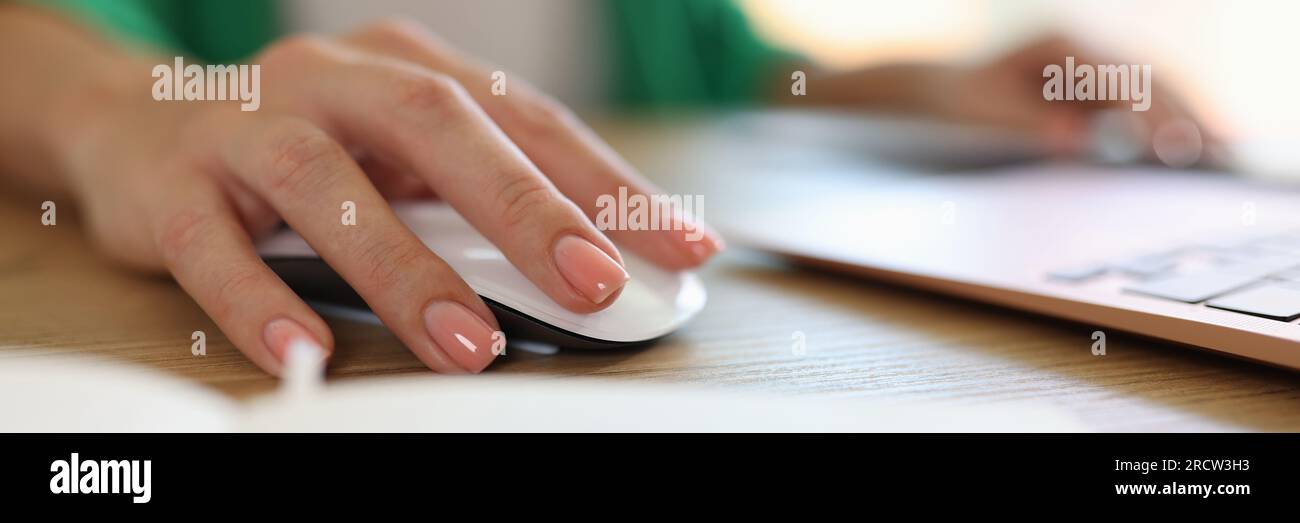 Employee holds computer mouse in her hand while working at office desk ...