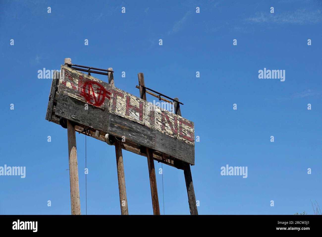 An old wood sign saying Nothing against a blue sky in the middle of the ...