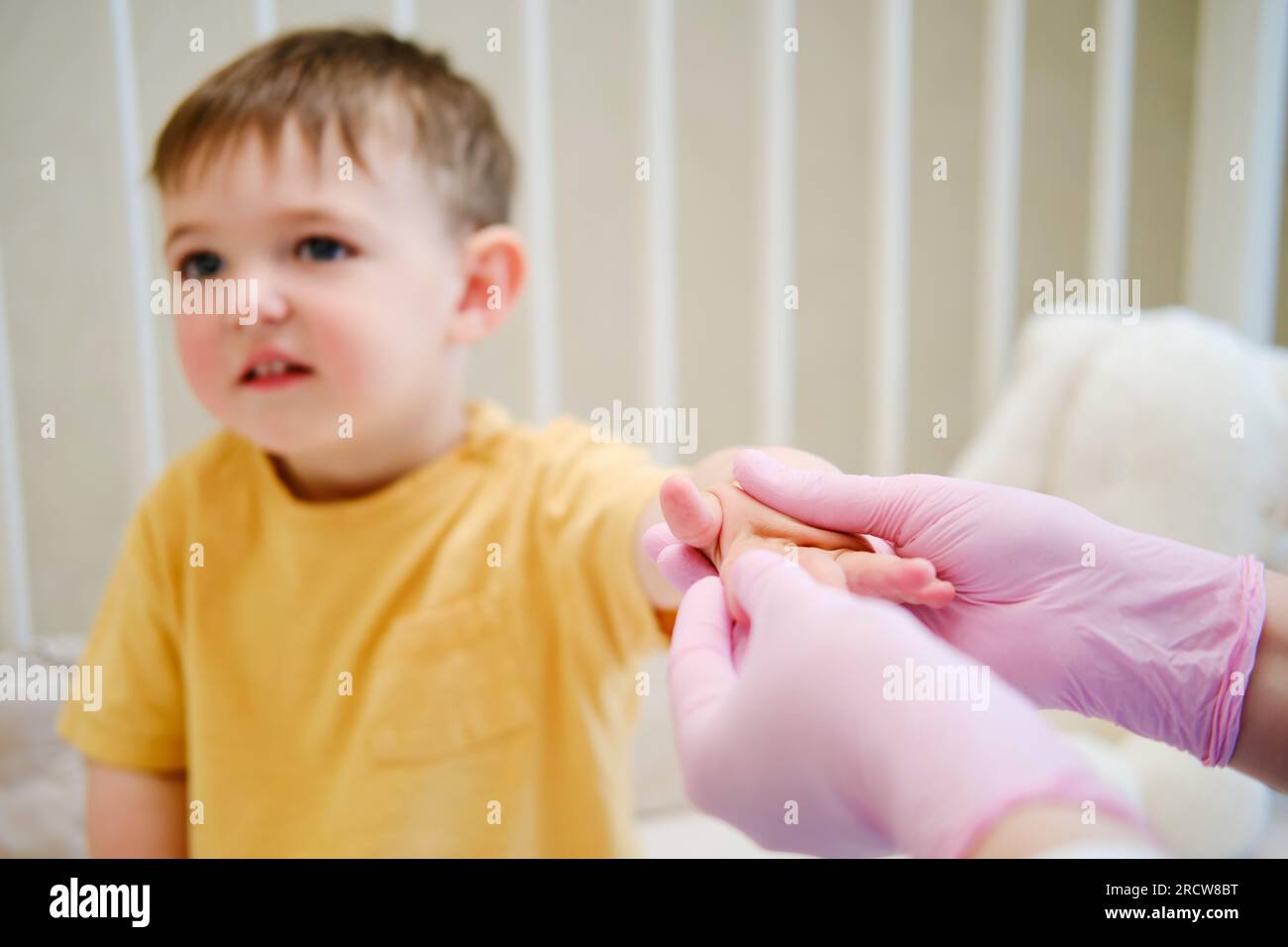 Doctor does gymnastics and hands massage to a toddler baby. Nurse in ...