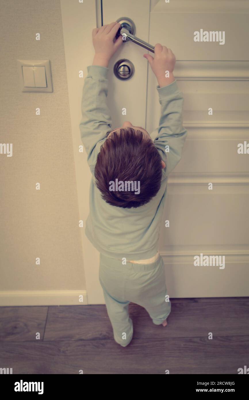 Little baby opens the door. Child pulls the door handle with the lock ...