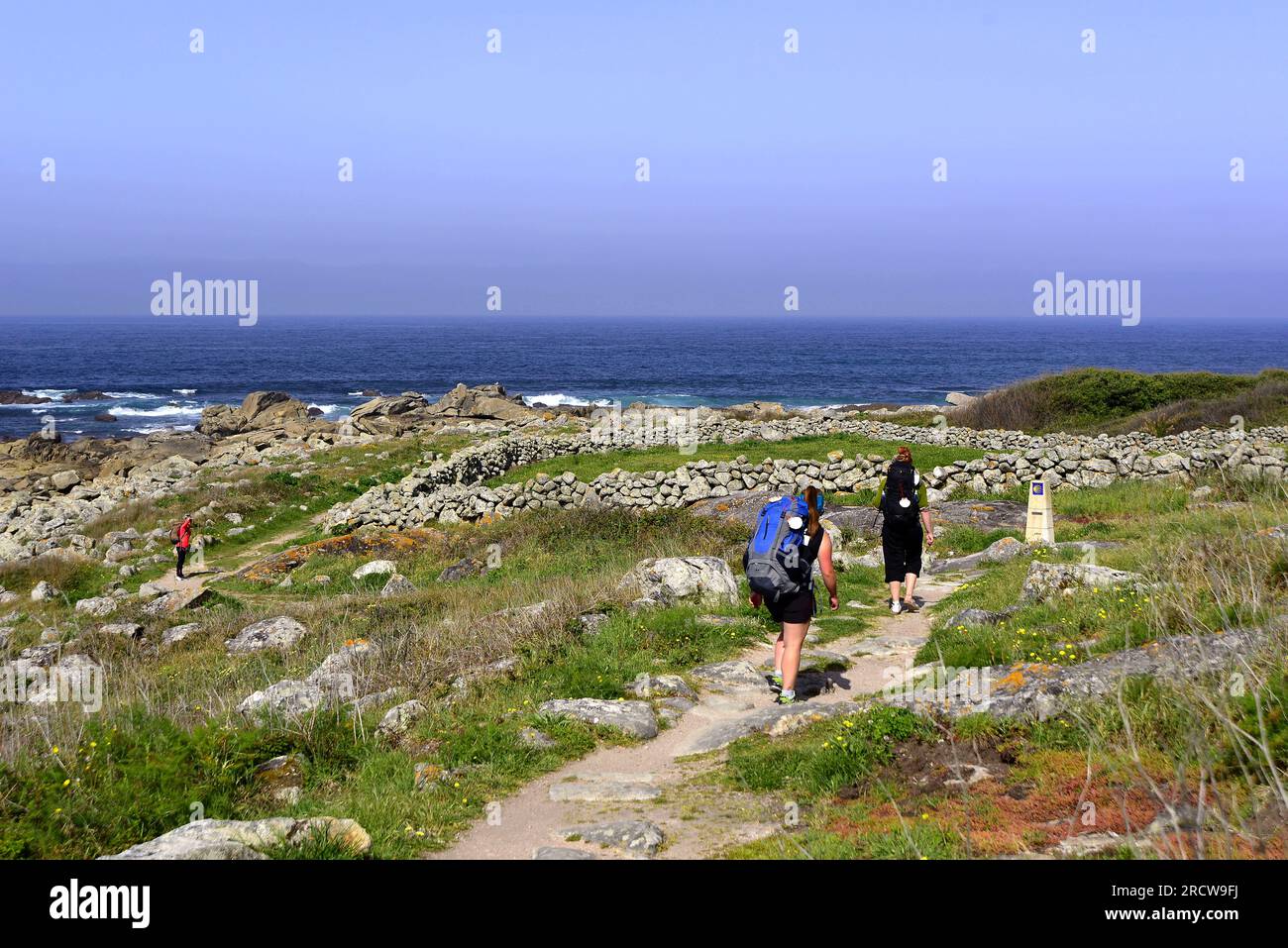 Two pilgrims on the Camino de Santiago walking on the shores of the ...