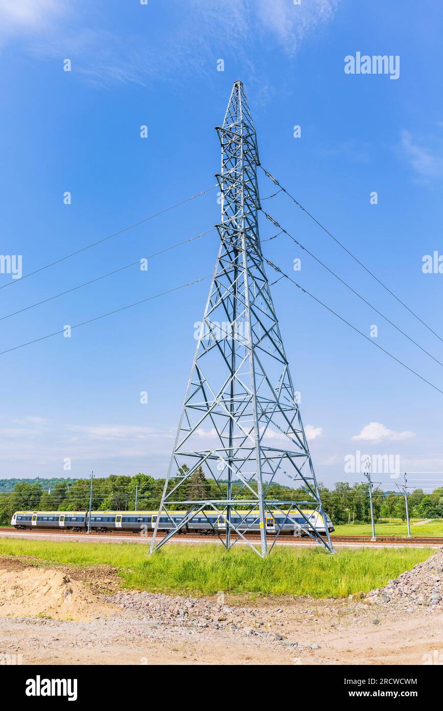 Electric power line by a railroad with a commuter train Stock Photo - Alamy