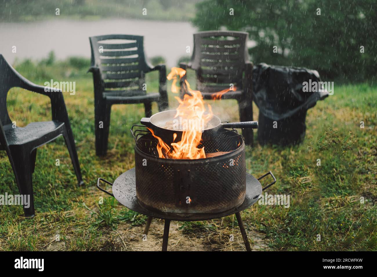 Man cooking fish on fire in nature, camping outdoors Stock Photo - Alamy